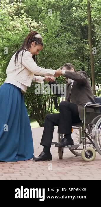 Attractive weak bearded 70-aged man trying to get up from wheelchair ...