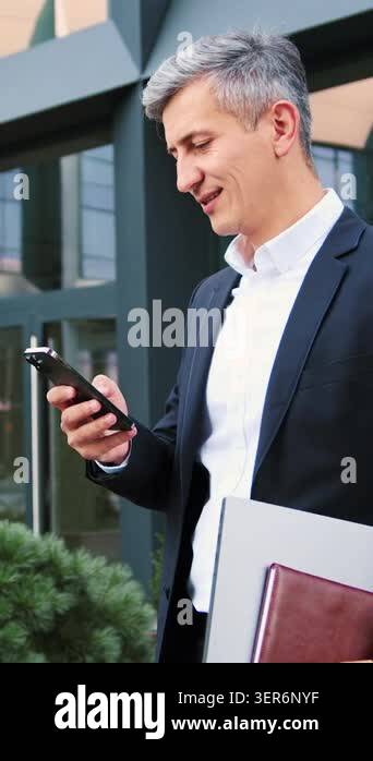 Man going outdoor with mobile phone in his hands. Middle aged ...