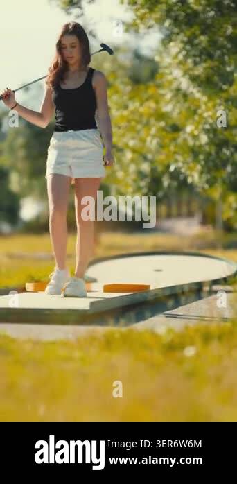 Girl is practicing her putting skills on a mini golf course at a park ...