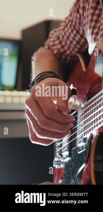 Close-up of a musicians hand playing a red electric guitar in a ...