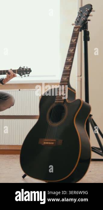 Young man musician composes music on the guitar and play in the kitchen ...