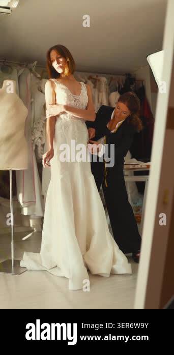 Female fashion designer taking measurements of a bride trying on a ...