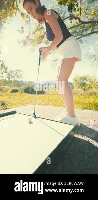 A young girl is outside in a park. She is setting up a hopscotch court ...