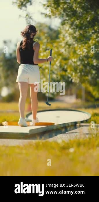 Player stands on platform and prepares to hit golf ball on mini golf ...