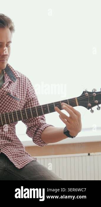Attractive young man musician composes music on the guitar and play ...