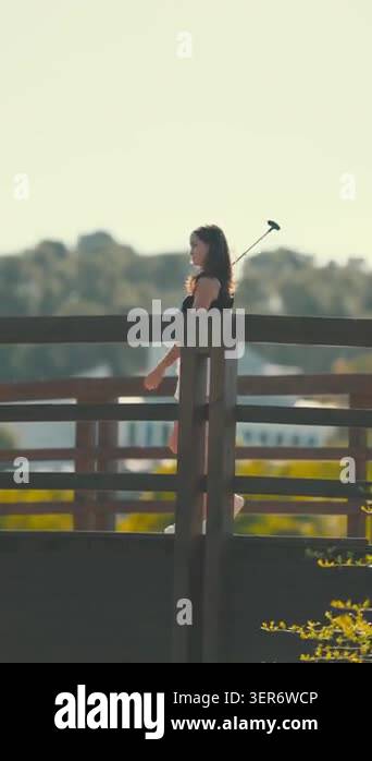 A person walks casually on a wooden bridge in a sunny location while ...