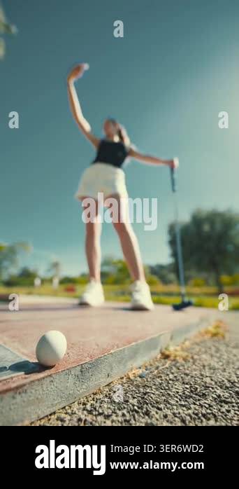 A person swings a club to hit a white golf ball on a warm sunny day at ...