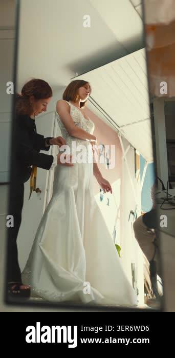 Female tailor fitting a white custom-made gown on a beautiful young ...