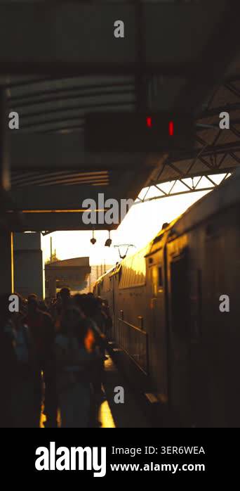 Passengers wait on the platform for the train to arrive. The sun sets ...