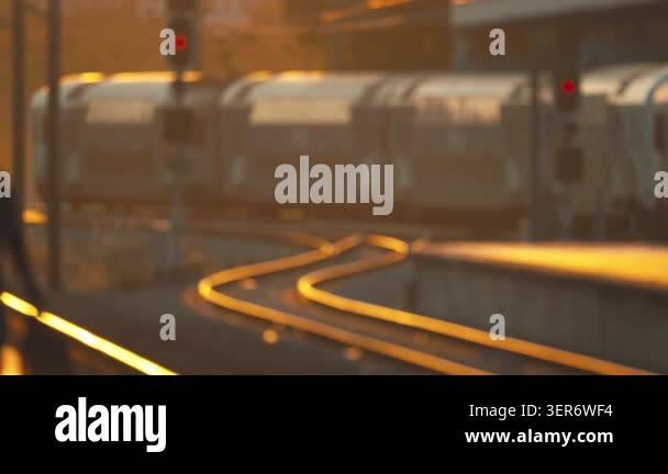 A train moves closer to the station as the sun sets. The tracks shine ...