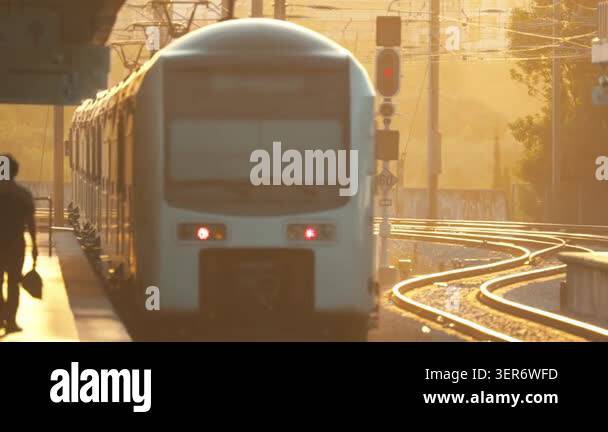 A person walks on a train platform as a train arrives in the evening ...