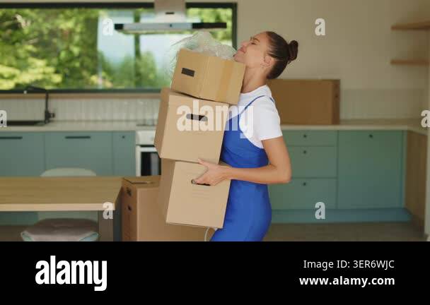 Young woman suffering while carrying stack of moving boxes and packing ...