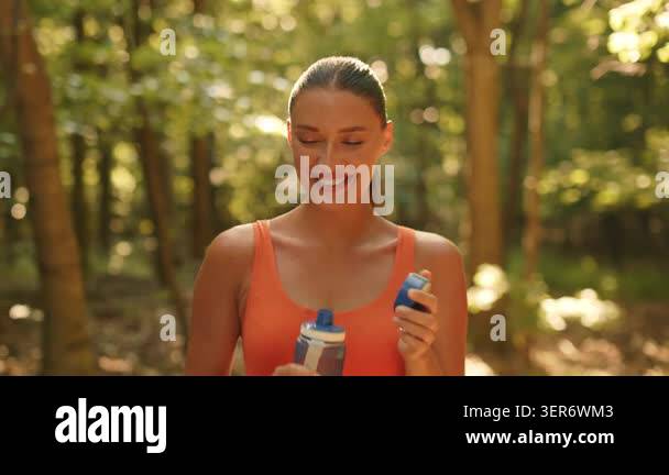 Happy woman smiling as opening water bottle and enjoying hydration ...
