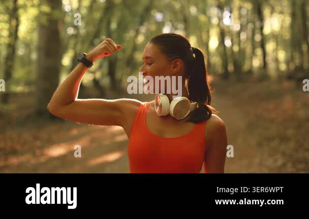 Happy lady runner showing her biceps and smiling at camera after ...