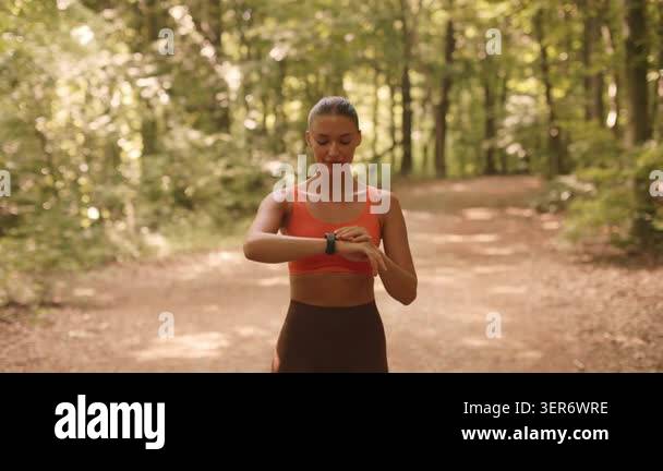 Woman in sportswear looking at smartwatch and starts jogging on ...