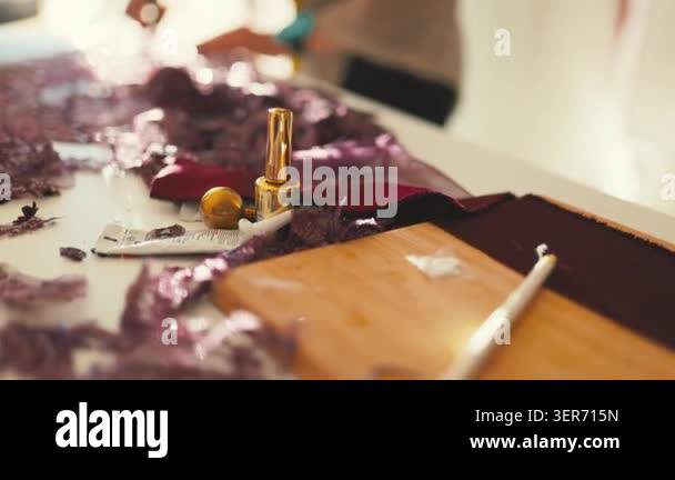 Dressmaker working on a new collection, cutting intricate details from ...