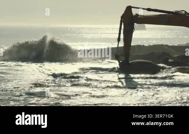 Heavy machinery excavator working on a beach, digging sand and moving ...