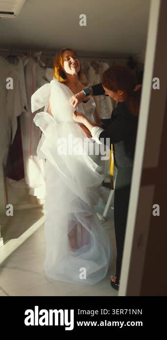 Professional tailor measuring and pinning a custom-made wedding dress ...