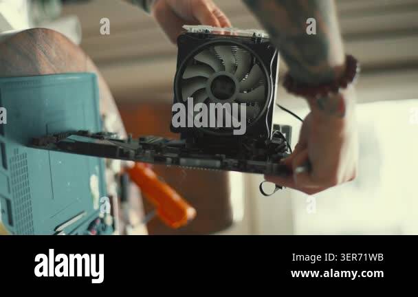 Computer technician with tattooed arms cleaning a dusty cpu cooler and ...