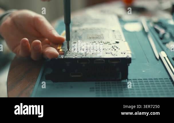 Skilled technician disassembling a computer video card with a ...