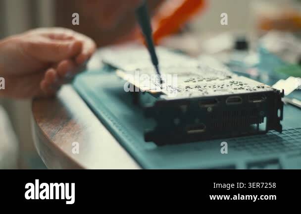 Technician using a screwdriver to disassemble a modern computer video ...