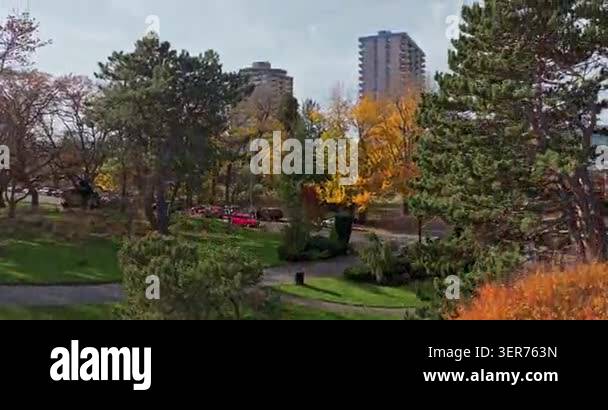 Aerial drone footage flying over a park with autumn trees and city ...