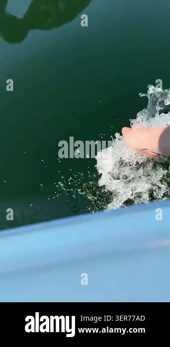 Close-up video of a hand gently touching the water surface while riding ...
