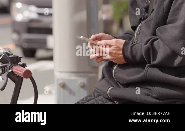 Slow motion Japanese man sits on a bicycle while using a smartphone on ...