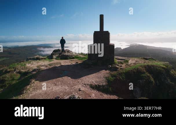Cinematic drone footage capturing a solitary man exploring the summit ...