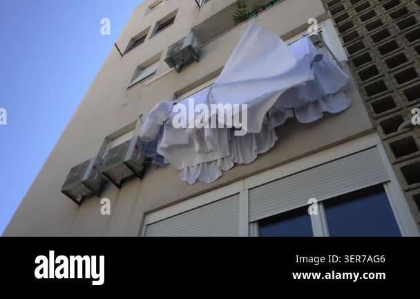 White laundry drying on clothesline on balcony of residential building ...