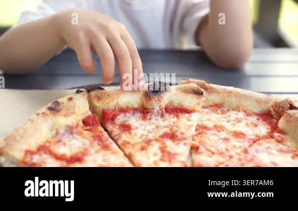 Close-up footage showing only a childs hands and a pizza on the table ...