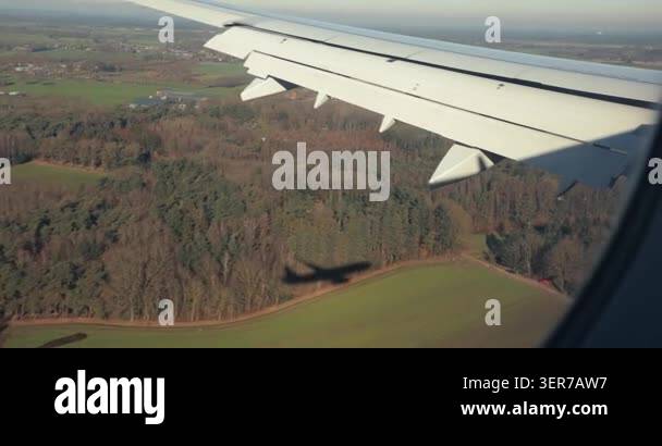 View from plane window at landing, shadow of the aircraft getting ...