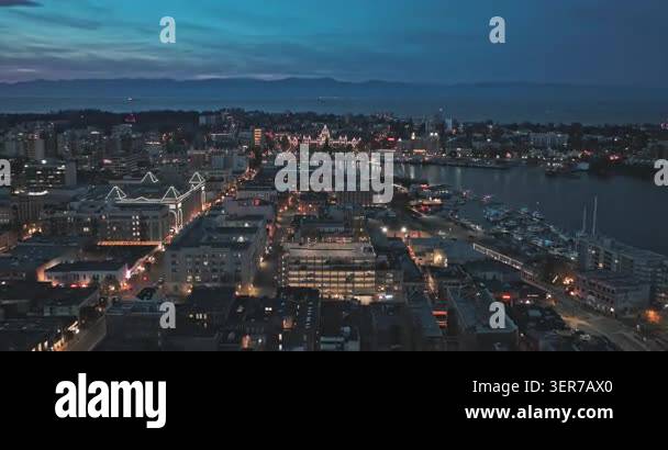 Aerial drone footage flying over a city at dusk, showcasing illuminated ...
