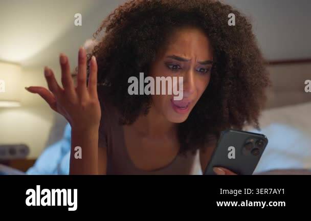 Shocked annoyed African American young woman upset with mobile phone ...