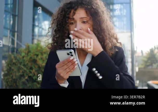 Caucasian amazed shocked business woman winning with mobile phone ...