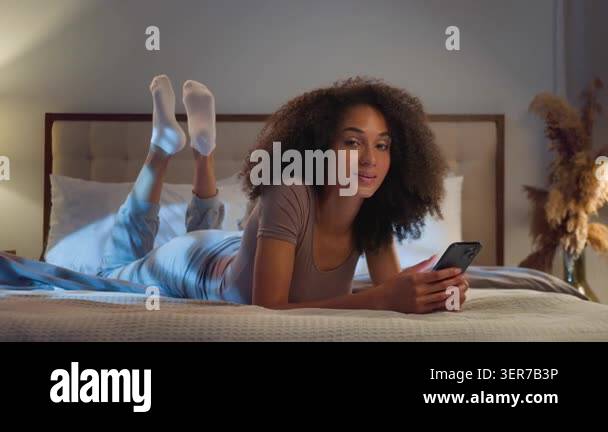 Relaxed African American woman enjoy mobile phone smile looking at ...