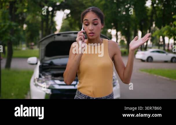 Worried African American woman talking mobile phone broken car accident ...