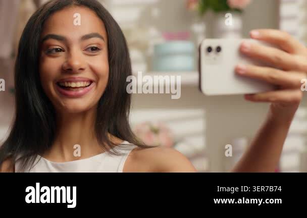 Smiling Latina ethnic girl greeting hello recording video with mobile ...