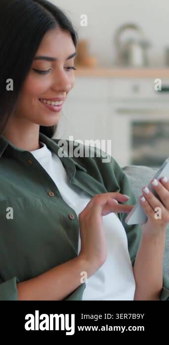 Happy relaxed Indian woman using mobile phone at home browsing social ...