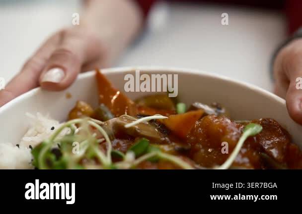Person holds a bowl of asian food filled with rice and colorful ...