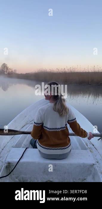 Woman rowing boat through misty river at peaceful sunrise. High quality ...
