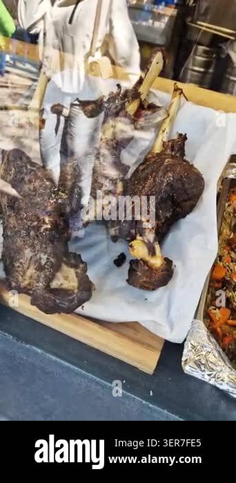 Herb seasoned roasted lamb shanks rest on white parchment paper behind ...