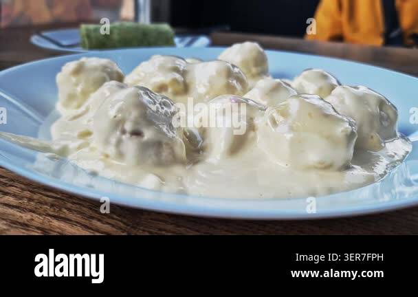 Savory meatballs are served smothered in a thick white cream sauce on a ...