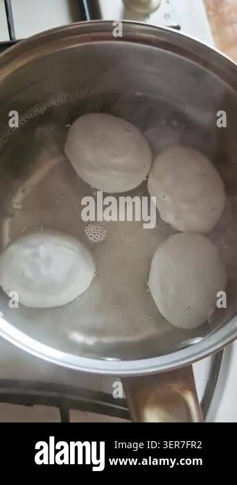 Four white eggs are actively boiling in bubbling hot water inside a ...