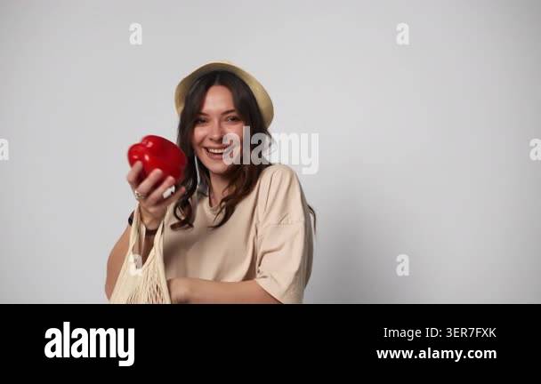 Young smiling woman in a straw hat holding a mesh bag with fresh ...