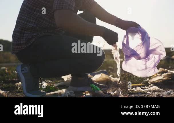 Male hands of eco activist in gloves collecting trash in bag at ...