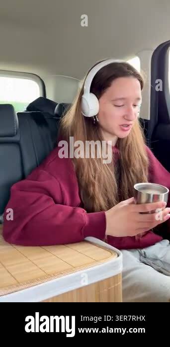 Teenage girl wearing headphones sings while watching tablet during ...