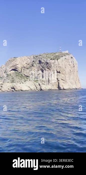 Massive rocky sea cliff rising above calm Mediterranean waters Stock ...