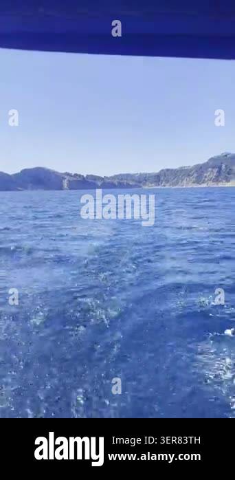 Open sea with distant rocky coastline and blue waters Stock Video ...