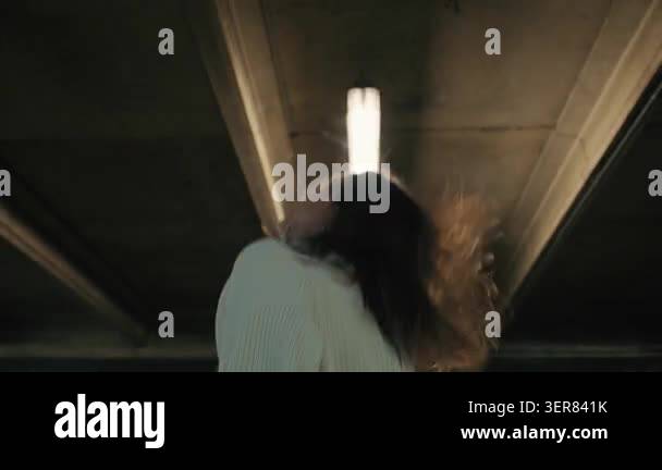 A stylish young woman dances with passion and energy in a dimly lit ...